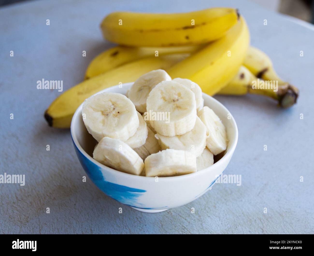 Sliced bananas in a bowl to prepare a fruit salad with whole bananas on ...