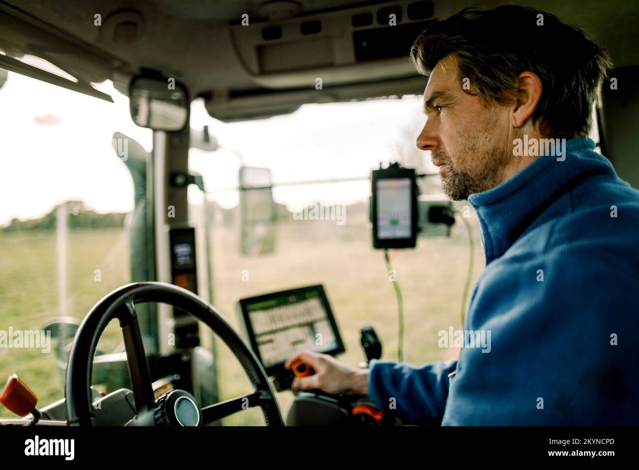 Mature farmer driving tractor on field Stock Photo - Alamy