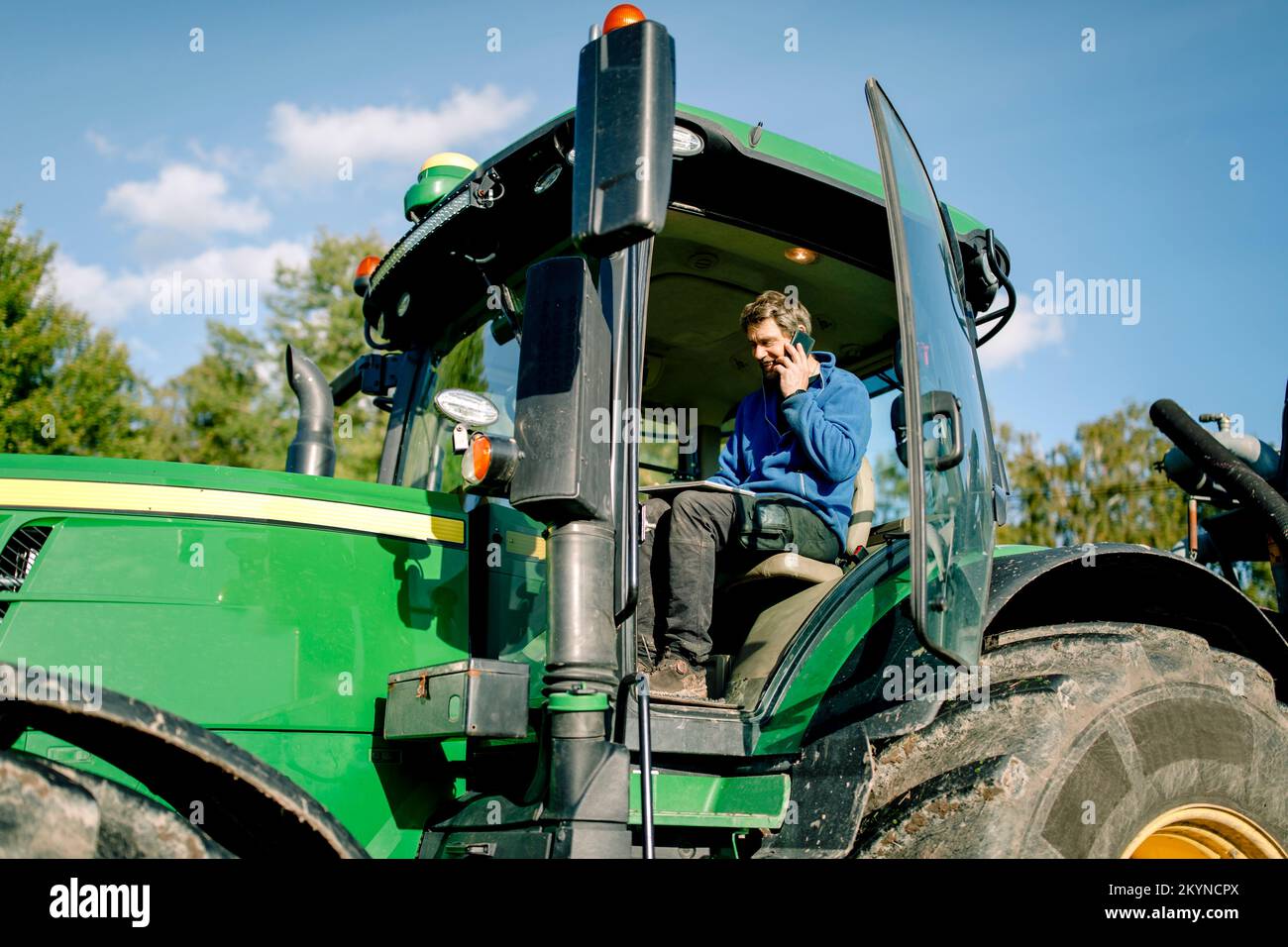 Farmer using tablet PC and talking on smart phone while sitting in ...
