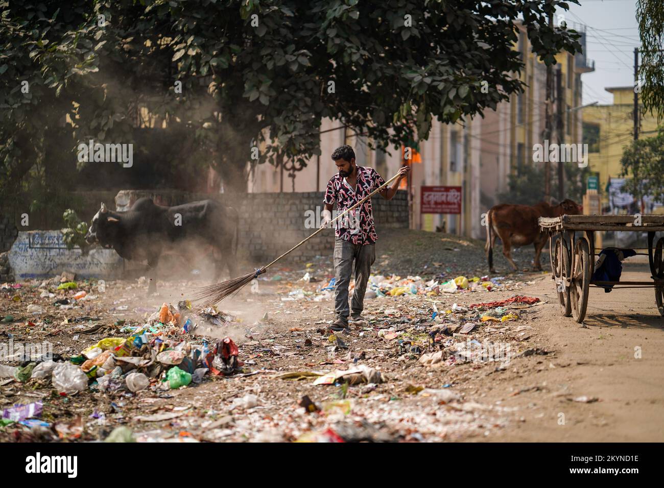 Man sweeping the trash with broom and polyhthene big garbage area, Man ...