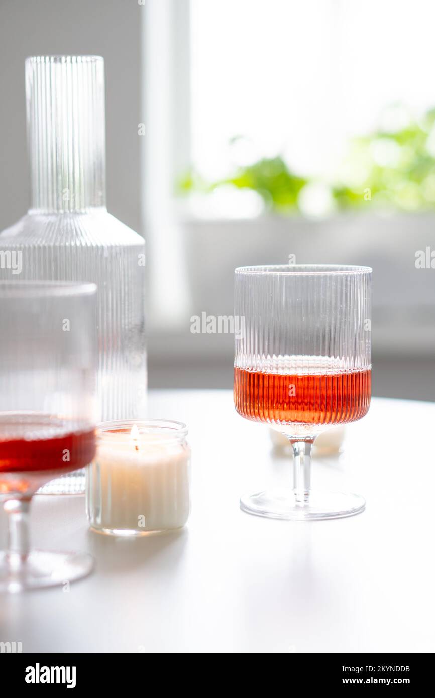 Rose wine in trendy ribbed wineglasses and decanter on white table ...