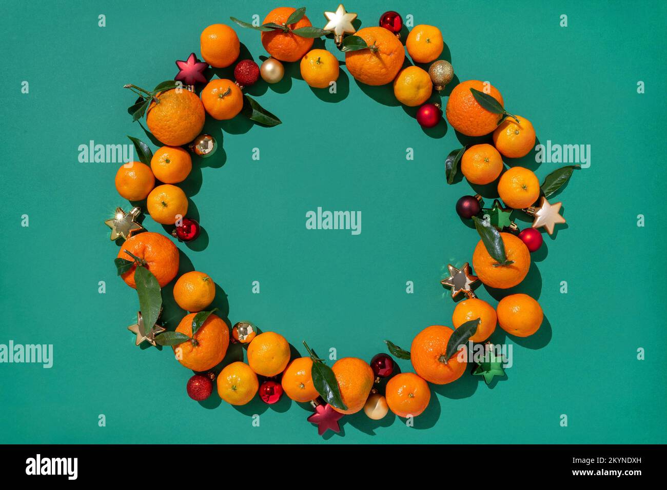 Christmas wreath of tangerines and fir-tree toys on green background ...