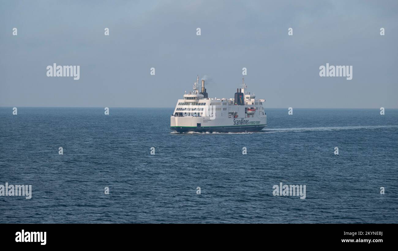 Large white ferry seen from a distance in blue water. Front view with ...