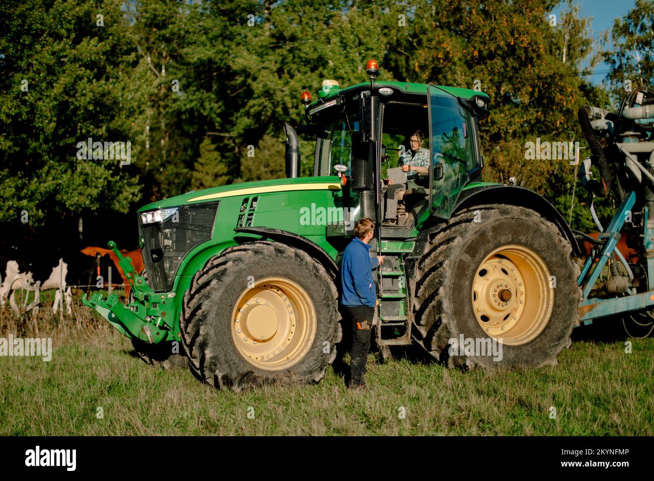 Farmer sitting in tractor and discussing with man standing at filed on ...