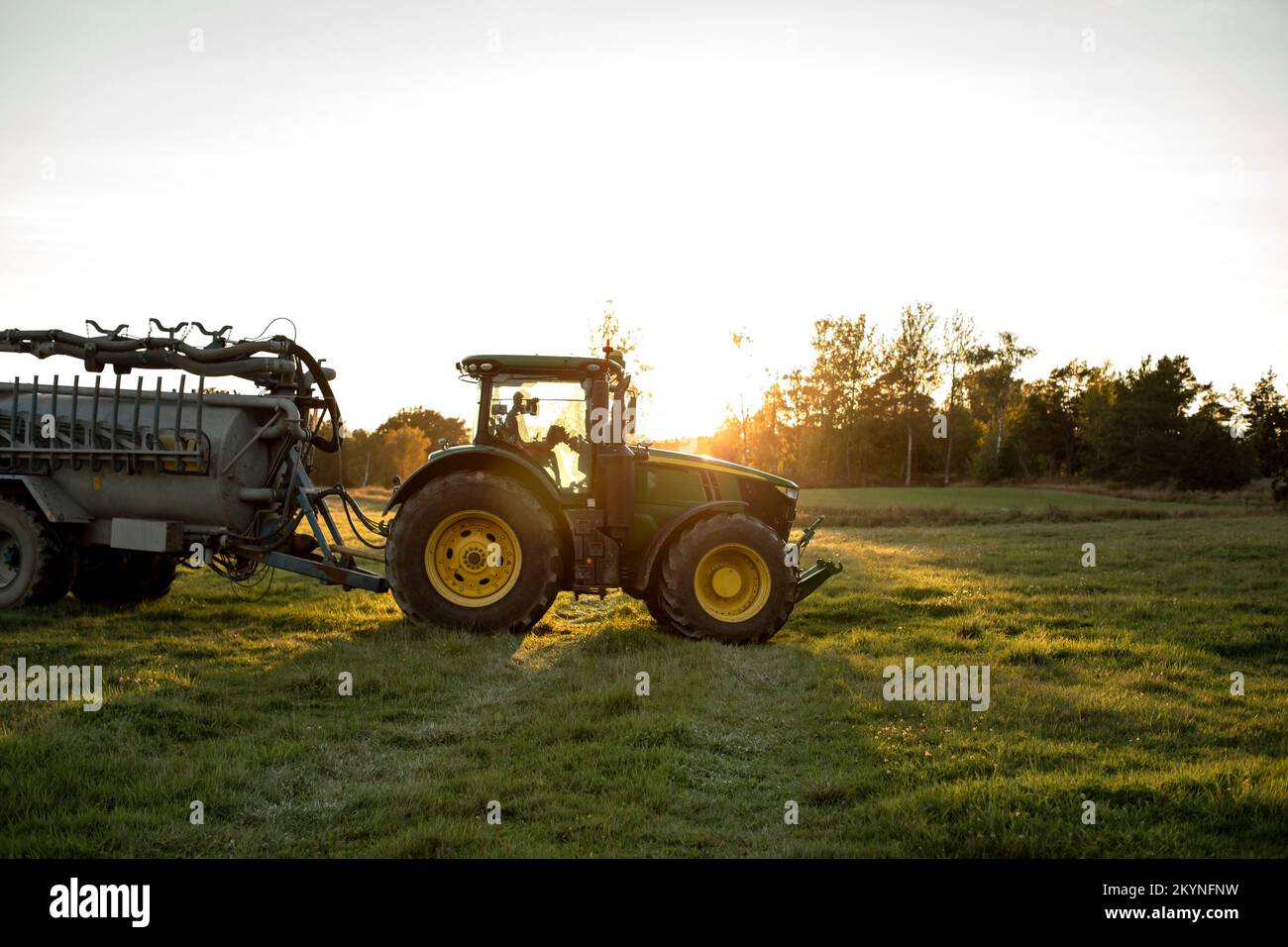 Tractor on field at sunset Stock Photo - Alamy