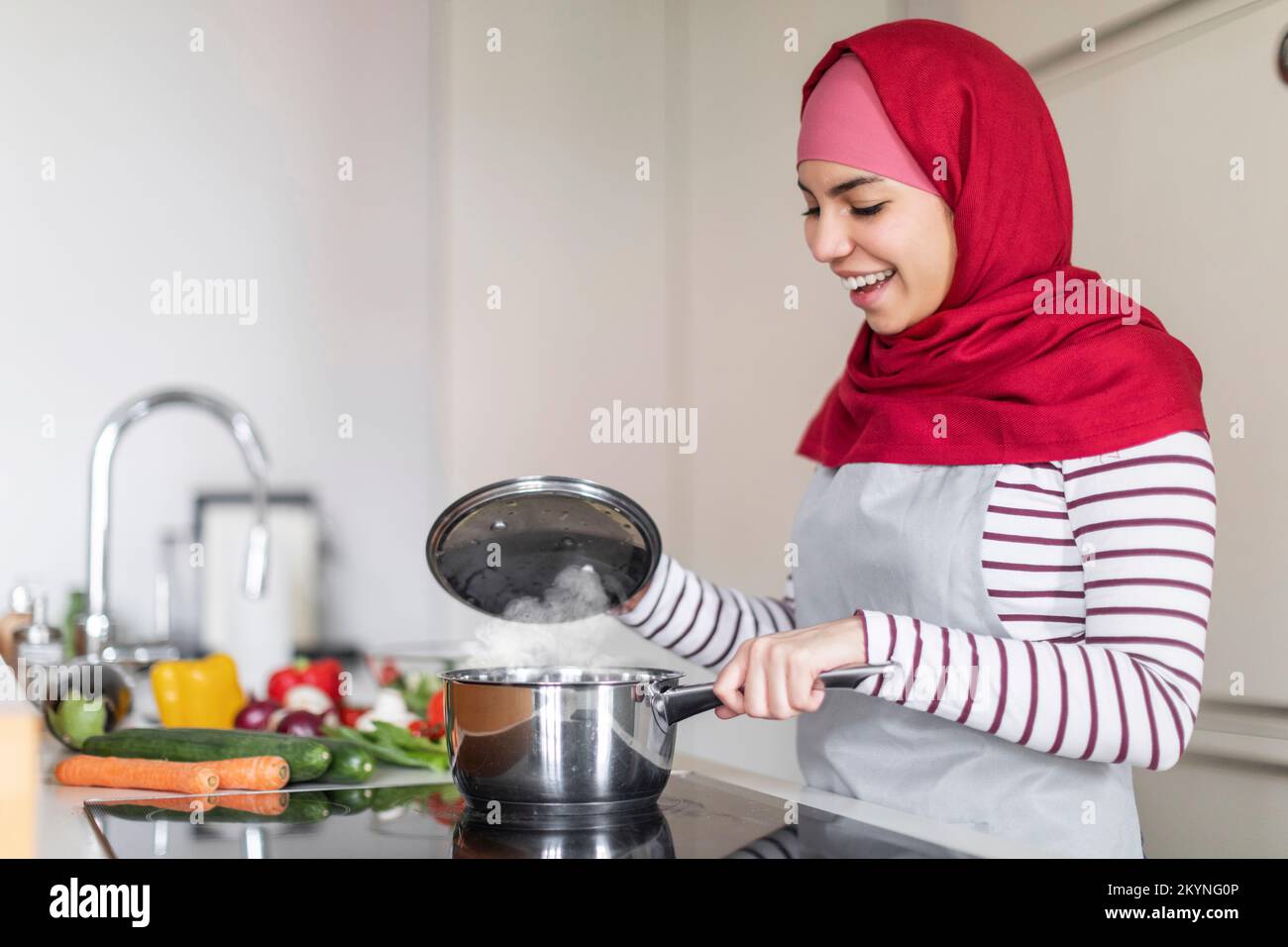 Middle eastern wife wearing hijab cooking at home, copy space Stock Photo - Alamy