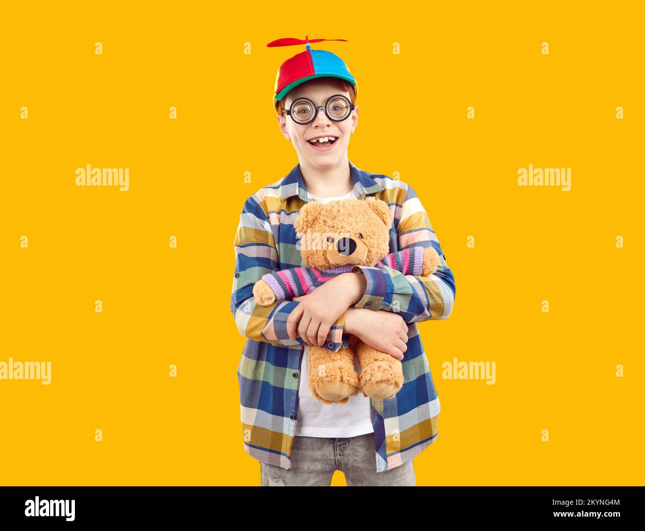 Happy school boy in propeller cap and funny glasses holding his teddy ...