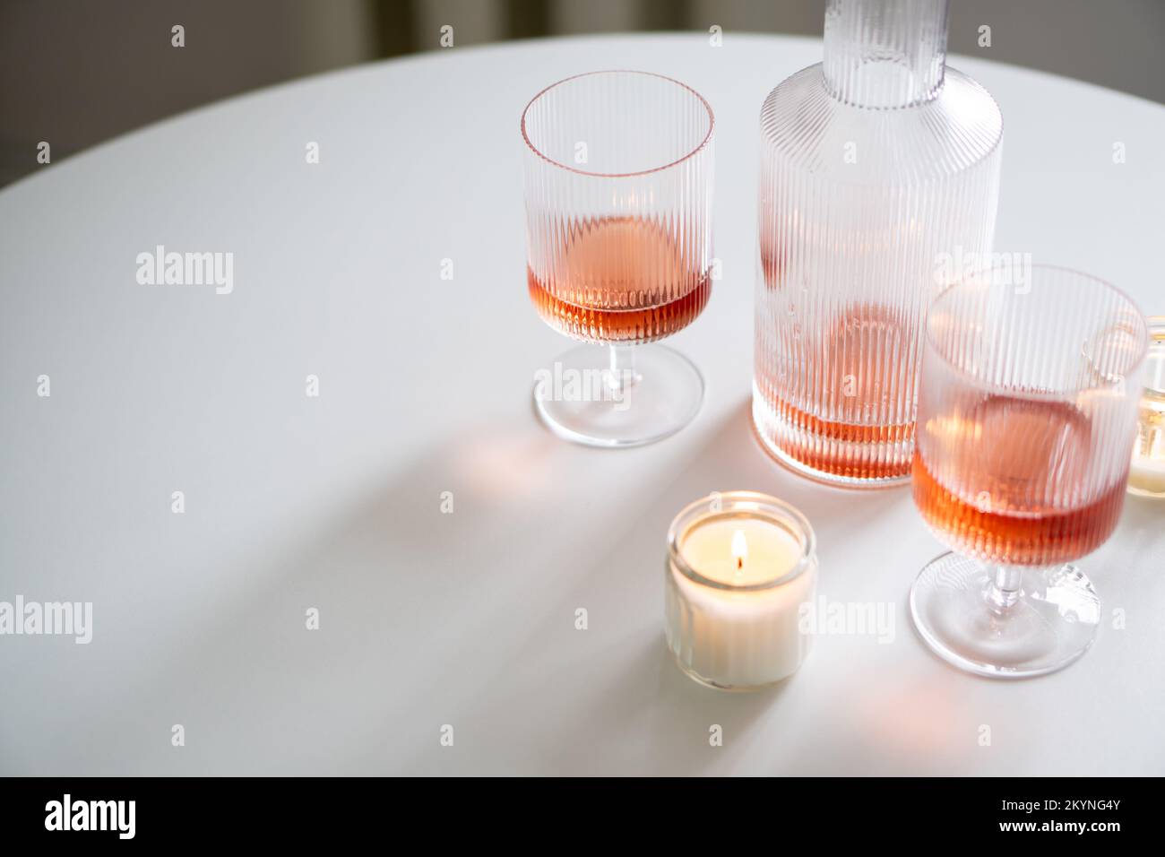 Rose wine in trendy ribbed wineglasses and decanter on white table ...