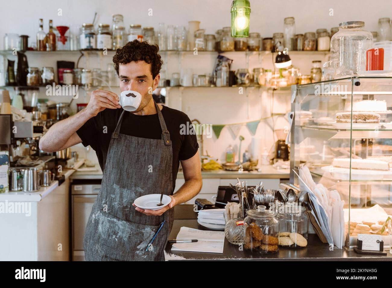 Male owner drinking coffee while standing near counter in cafe Stock ...