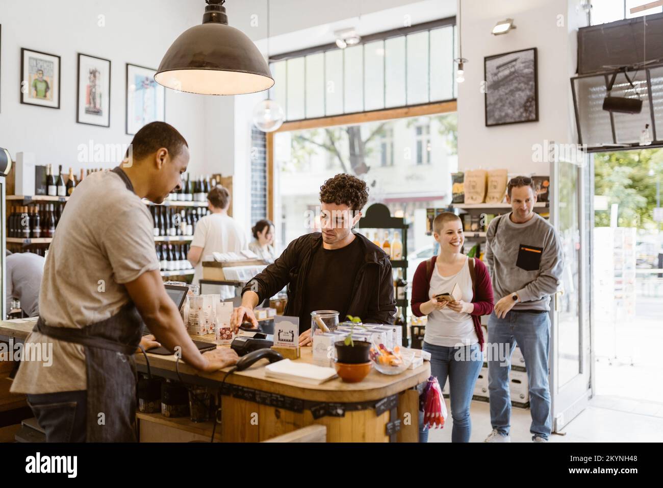 Male customer paying at checkout counter while doing shopping in deli ...