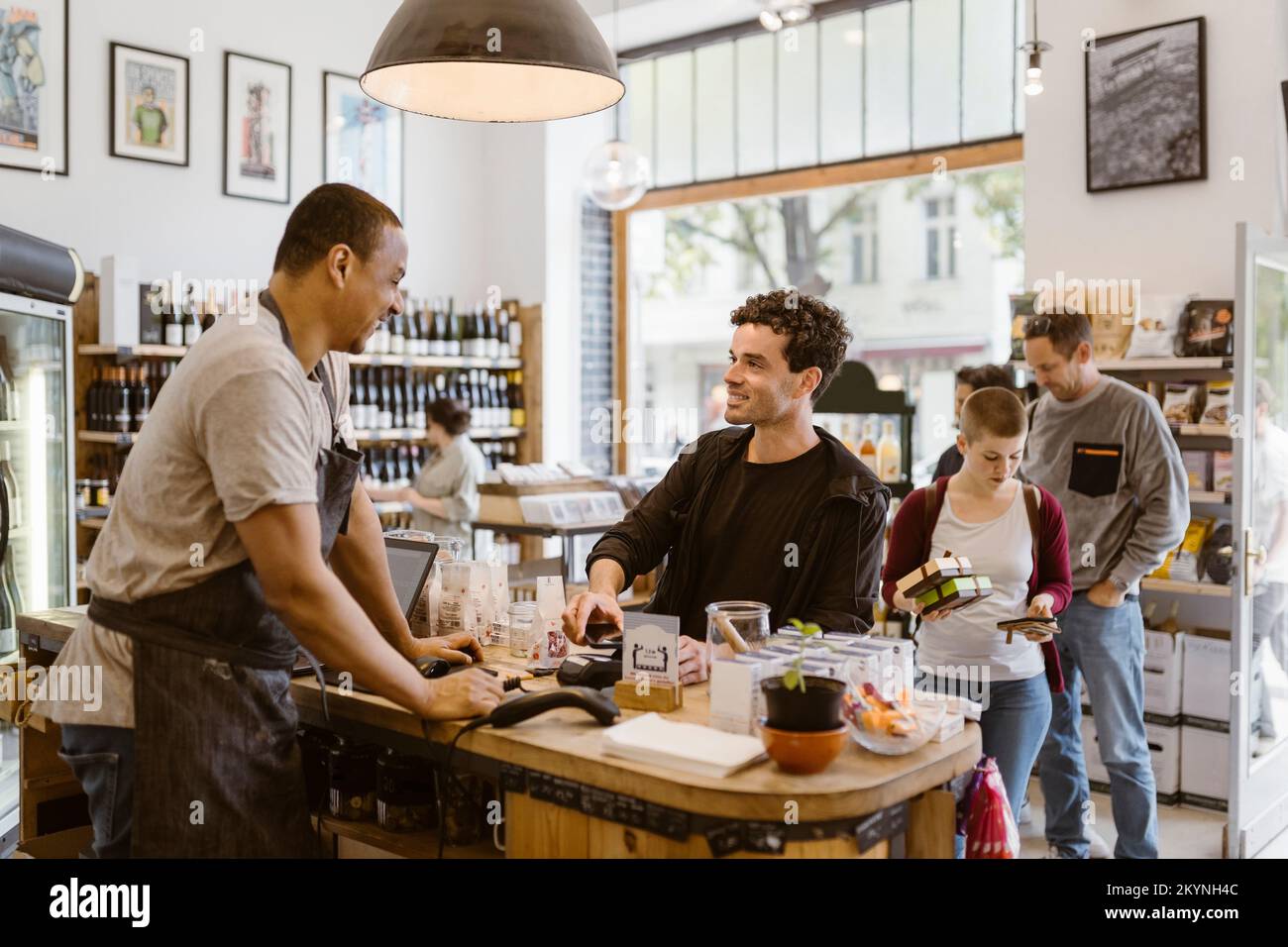 Male owner talking with customer at checkout counter in store Stock ...