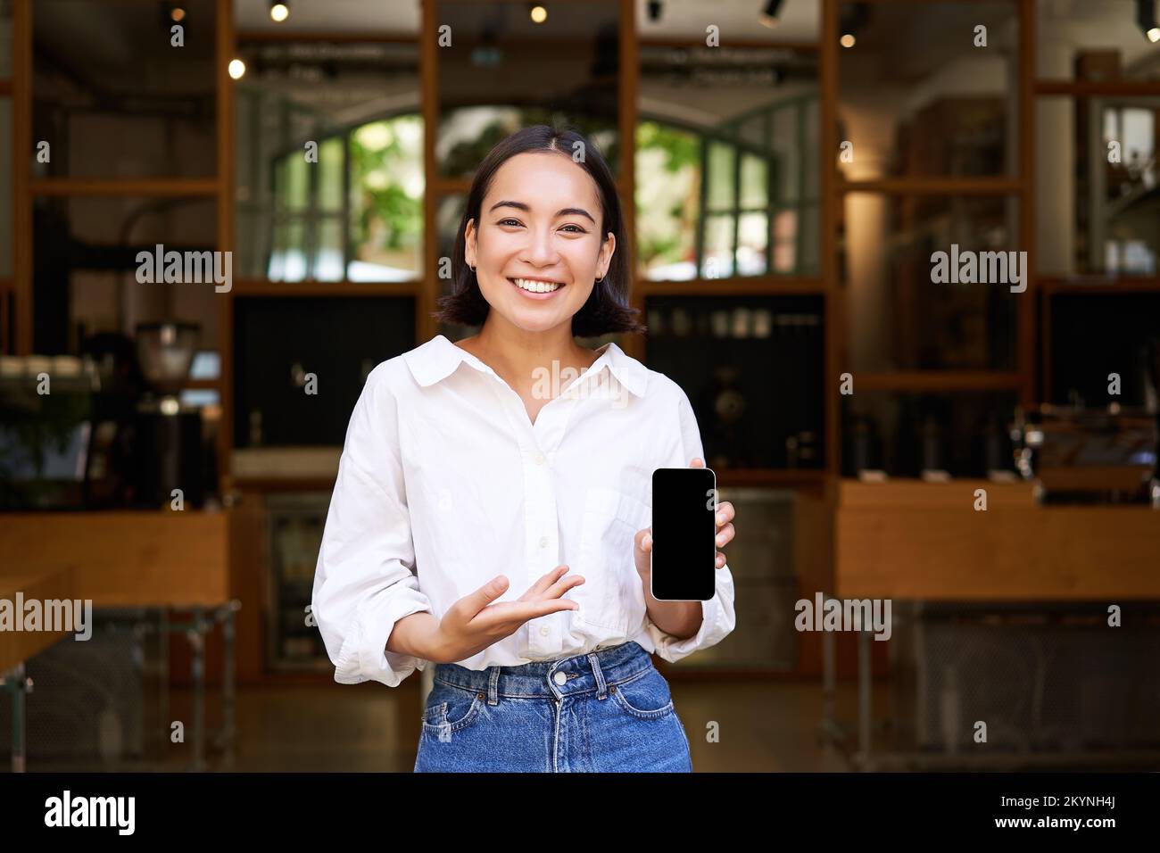 Enthusiastic young asian woman, cafe manager demonstrating app on ...