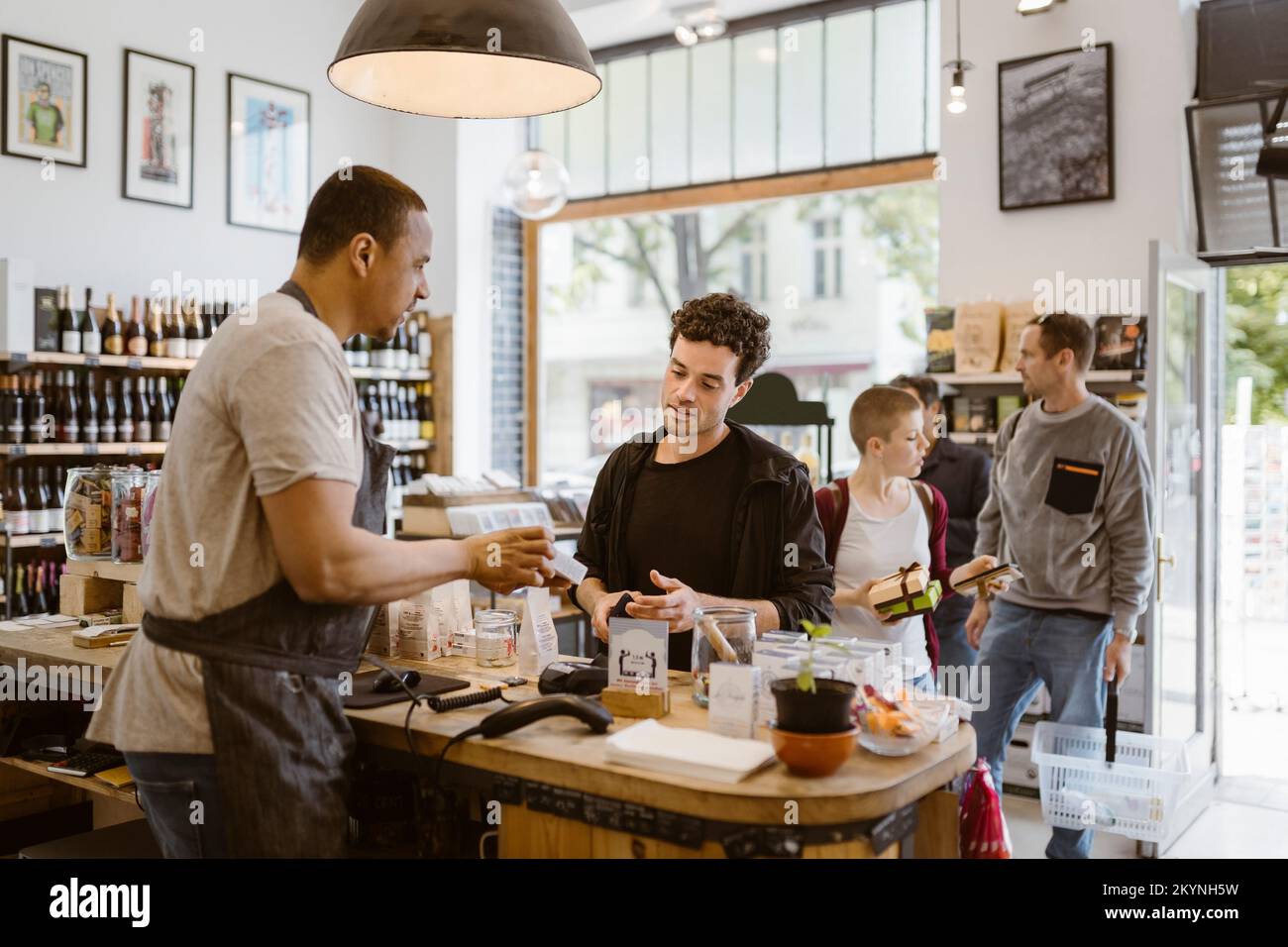 Side view of male owner explaining product to customer at checkout ...