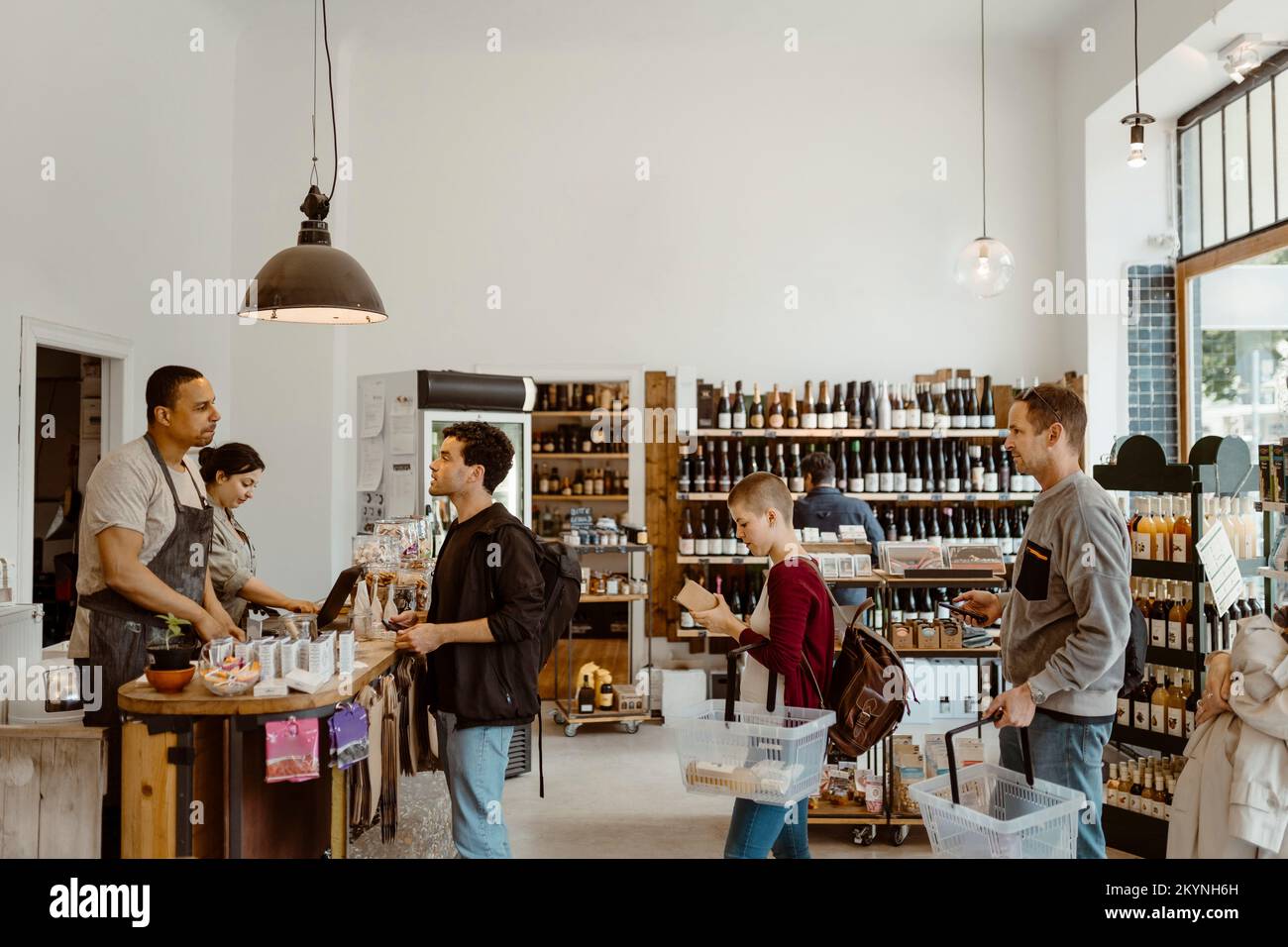 Customers standing in queue while doing shopping in store Stock Photo ...