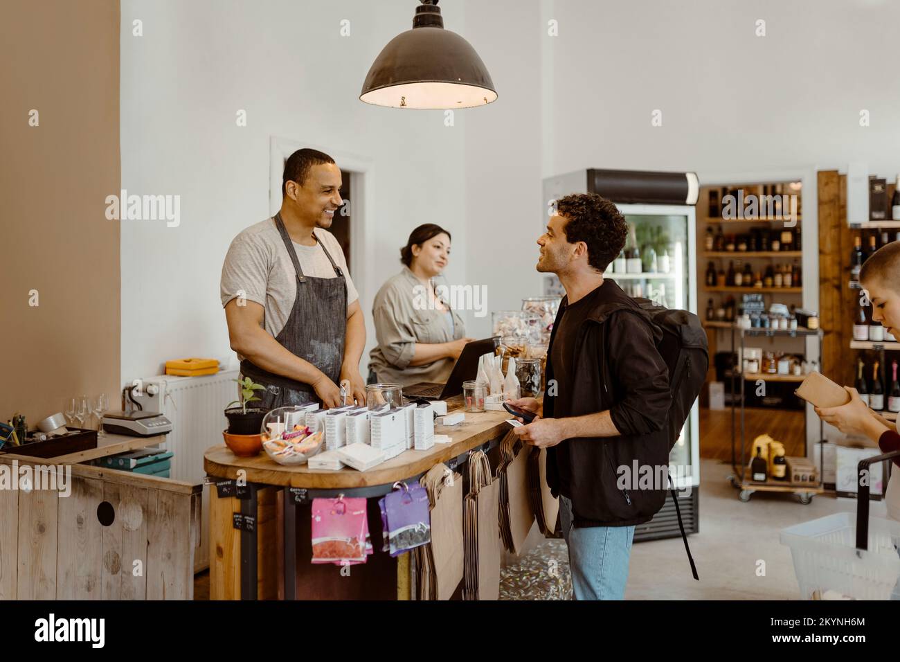 Side view of male customer interacting with store owner standing at ...