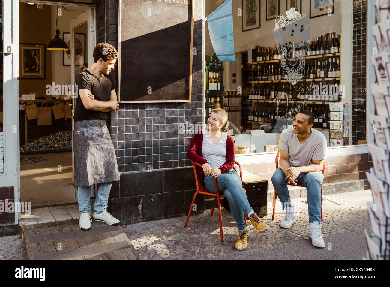 Customers talking to male owner standing by store doorway Stock Photo ...