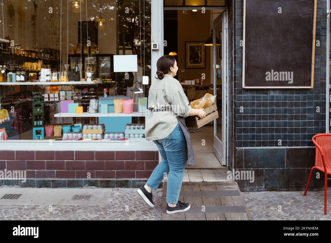 Female owner walking inside store holding crate Stock Photo - Alamy