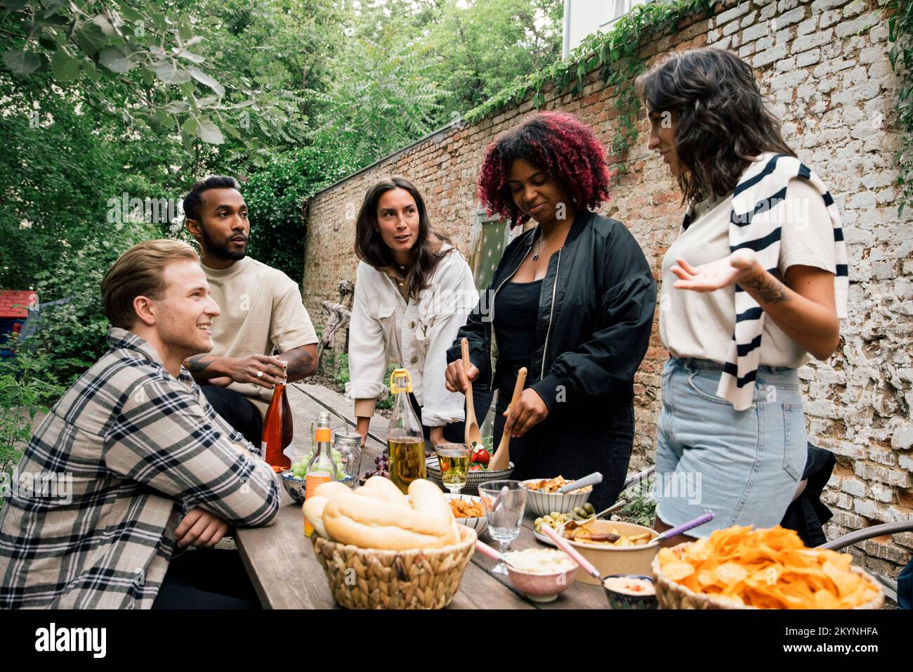 Multiracial male and female friends talking to each other during social ...