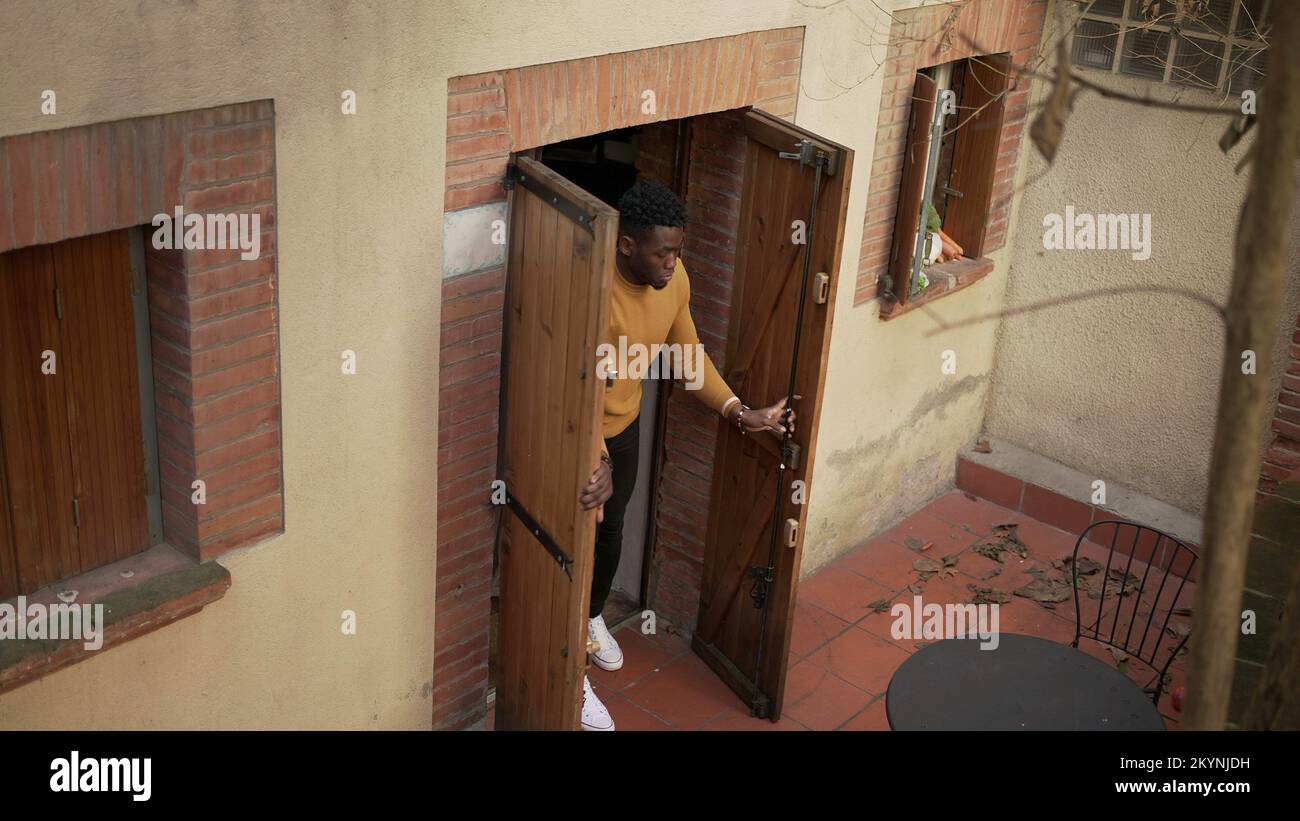 Young black man closing front door home. African person closes house ...