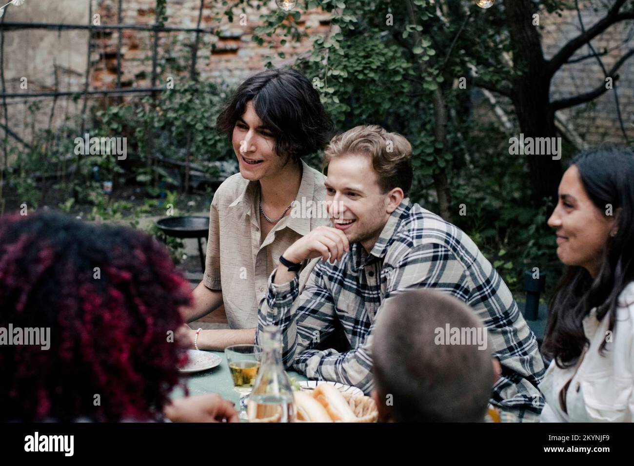 Friends talking with each other during social gathering in back yard ...