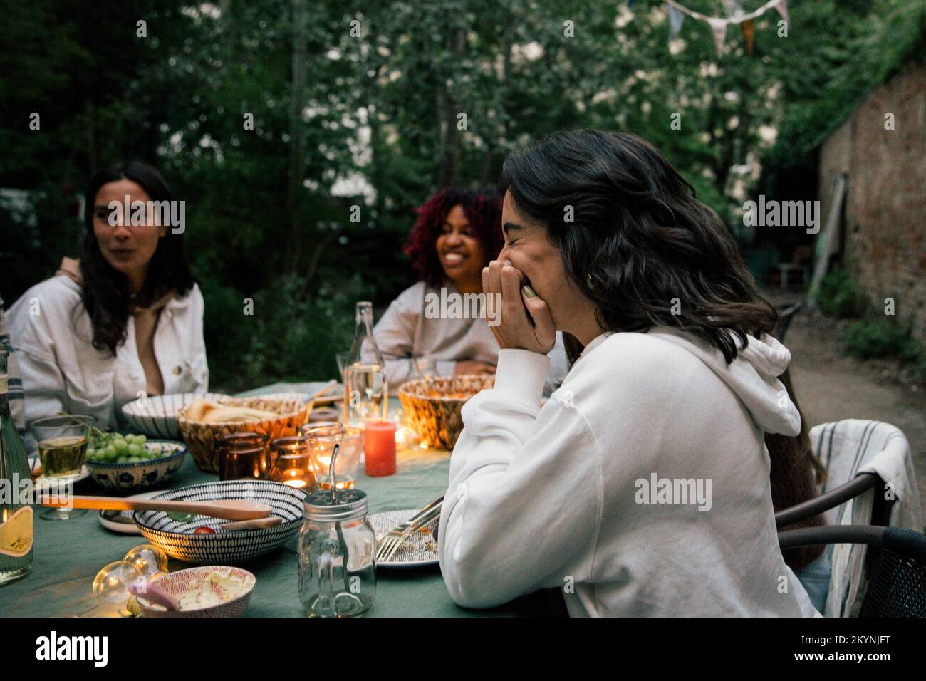Side view of woman laughing while sitting at dining table during dinner ...