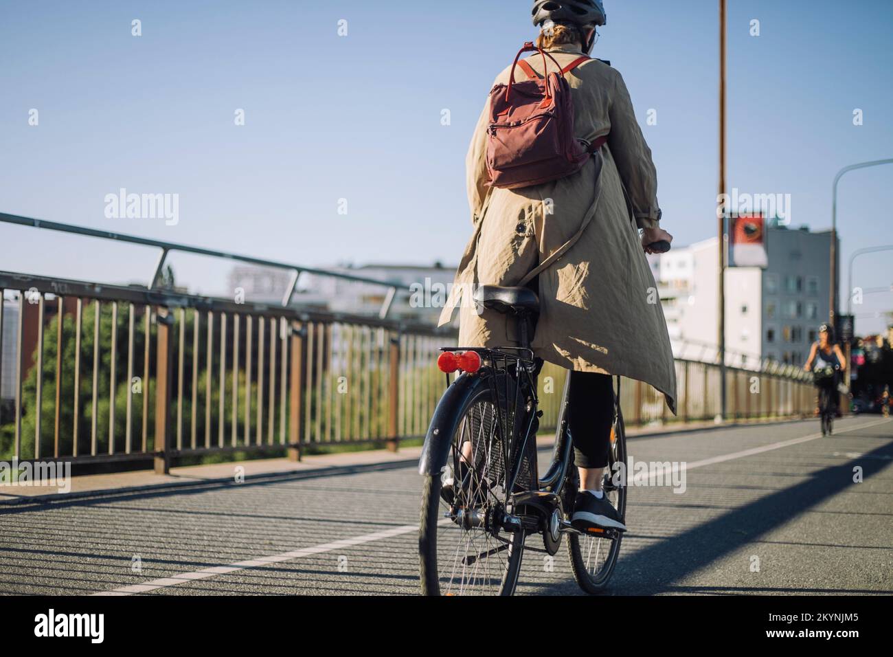 Rear view of businesswoman with backpack riding bicycle on lane Stock ...
