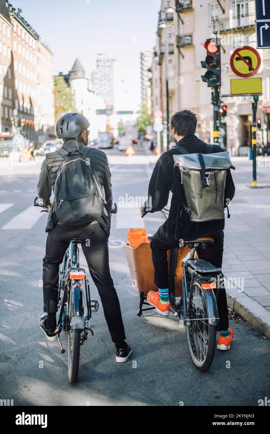 Businessmen with cargo bike and bicycle waiting at traffic signal on ...
