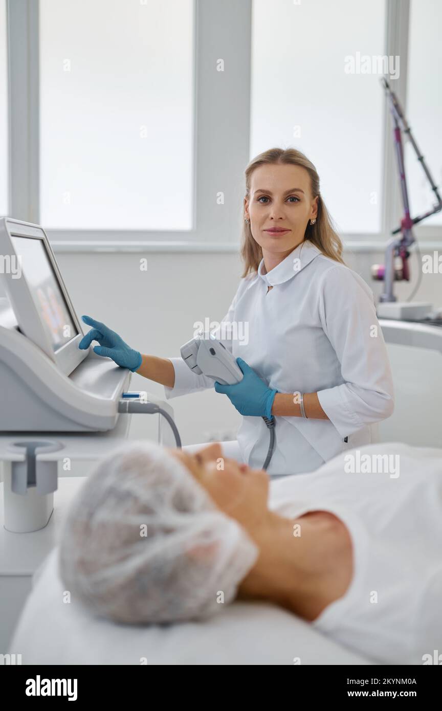 Portrait of female cosmetologist working with laser machine Stock Photo ...