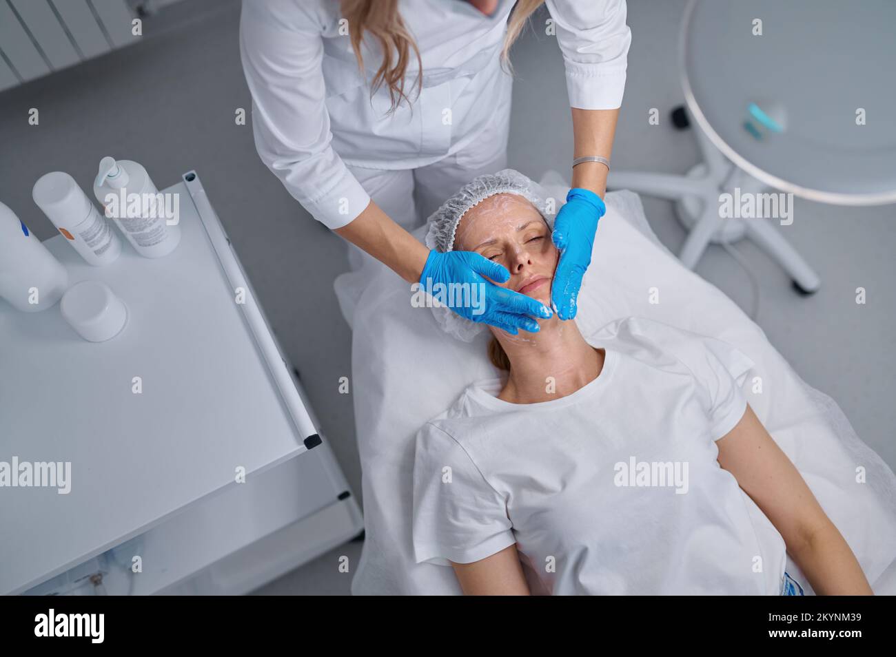 Woman professional doctor beautician applying mask on patient face for ...
