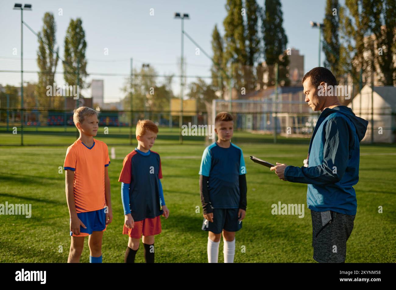 Young soccer coach teaching kids on football field Stock Photo - Alamy