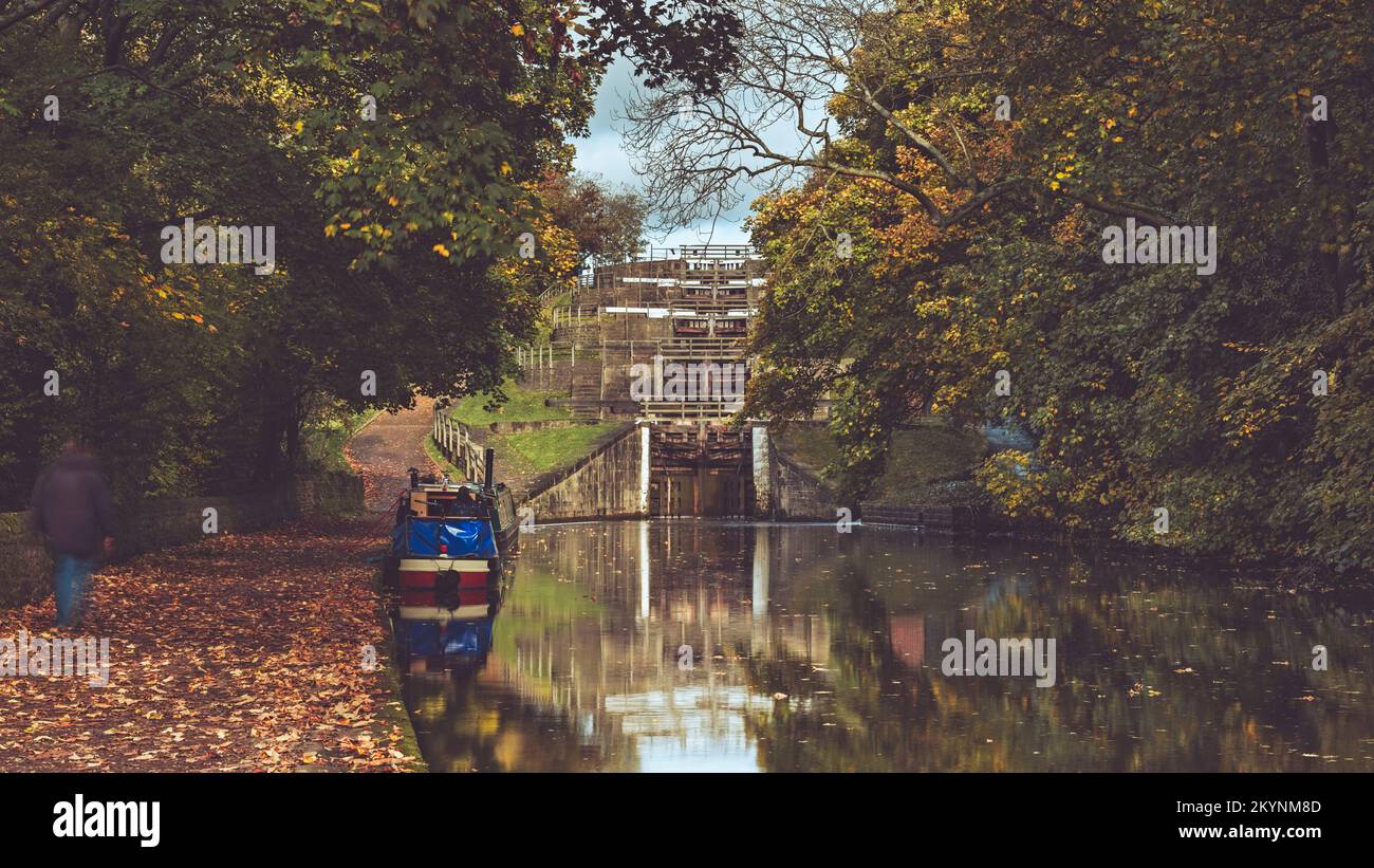 Barge on sunlit rural waterway, person walking on footpath, autumn ...