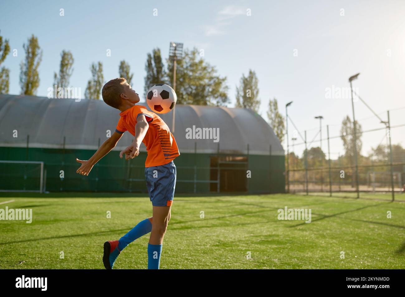 Junior football player jumping to hit soccer ball with chest Stock ...