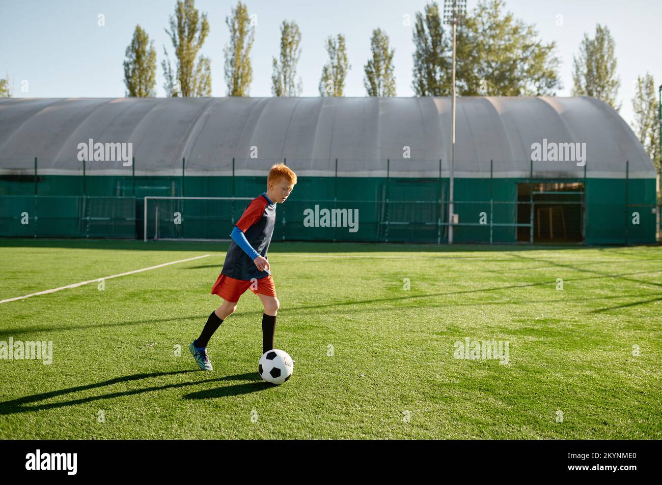 Elementary age football player kicking ball training along on soccer ...