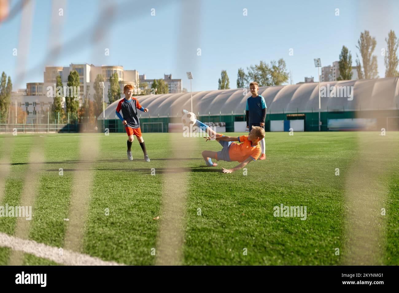 Junior forward jumping to kick ball with leg taking part in football ...