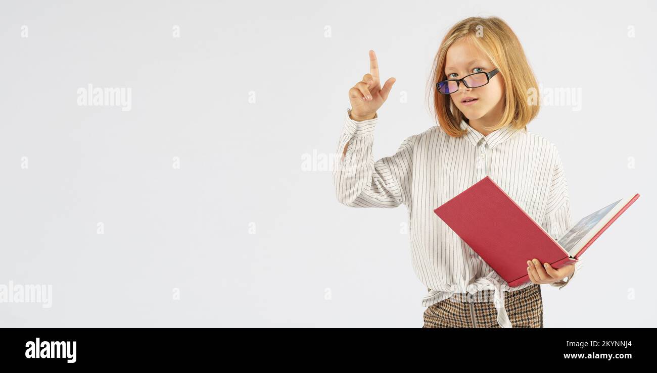 A teenager girl holding an open book in her hands and raised her finger ...