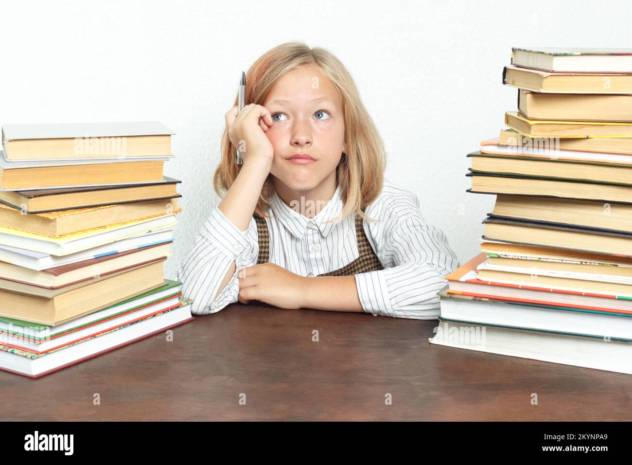 Portrait of a teenage girl, at a table among the books. Looks tiredly ...