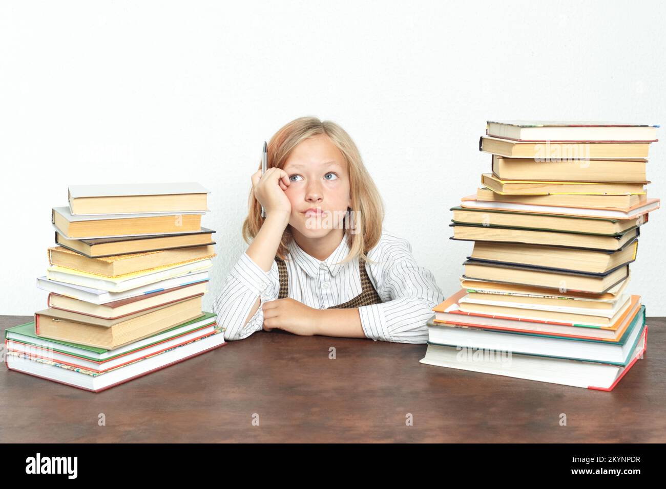 Portrait of a teenage girl, at a table among the books. Looks tiredly ...