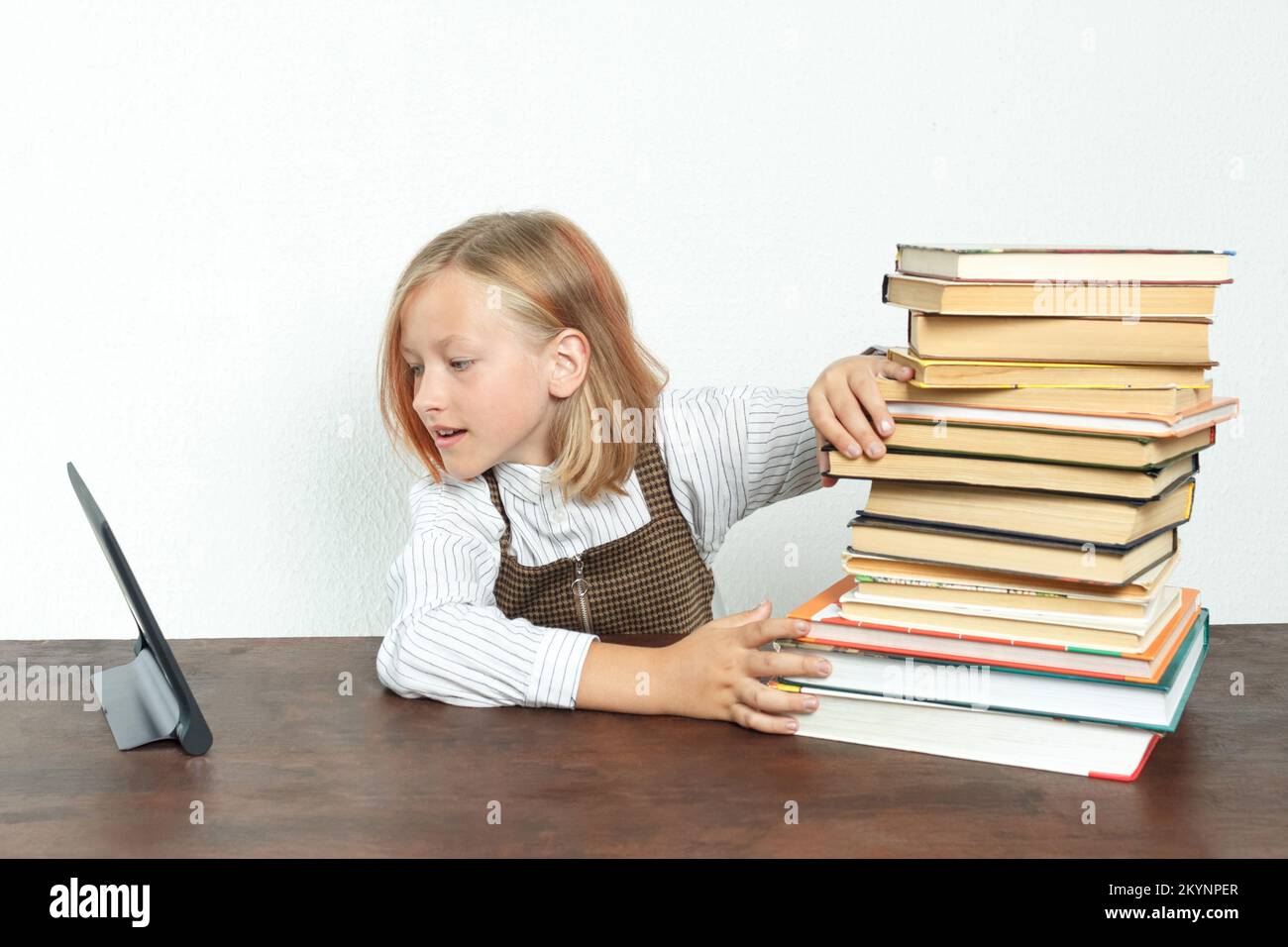 Education concept. Teenage girl pushes books aside, choosing a tablet ...