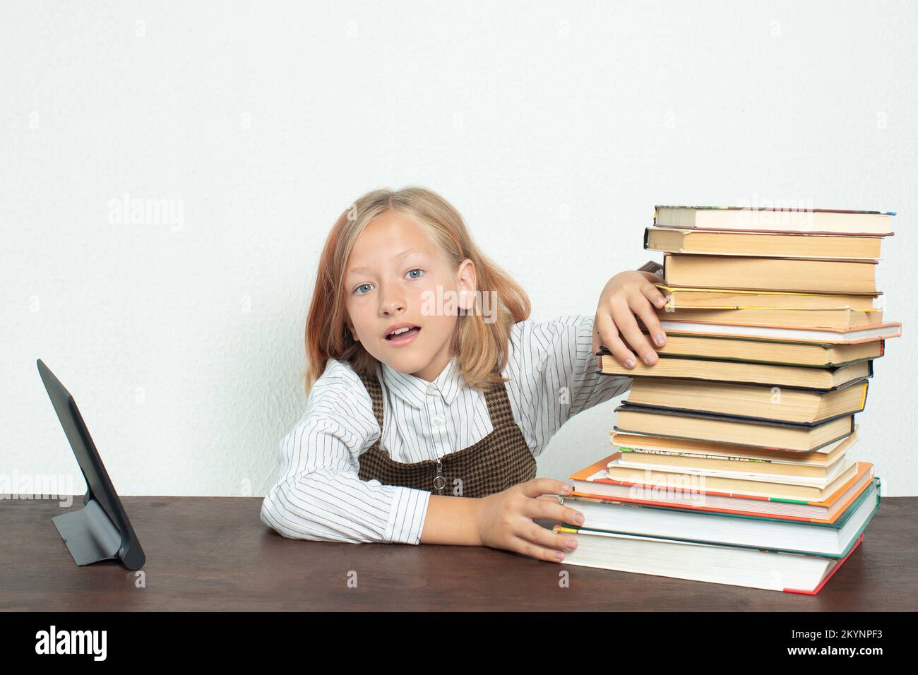 Education concept. Teenage girl pushes books aside, choosing a tablet ...