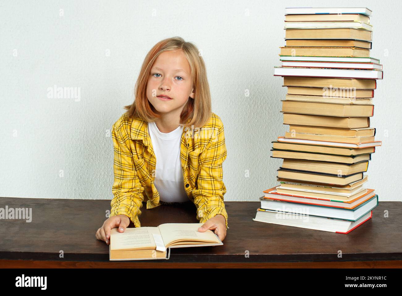 Education concept. A teenage girl is sitting at a table and reading a ...