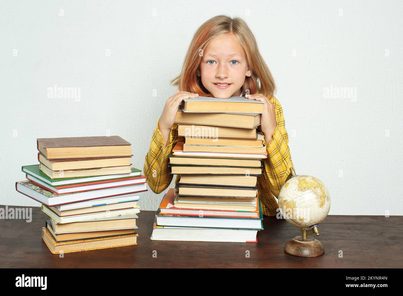 Education concept. A teenage girl stands near a table with books, her ...