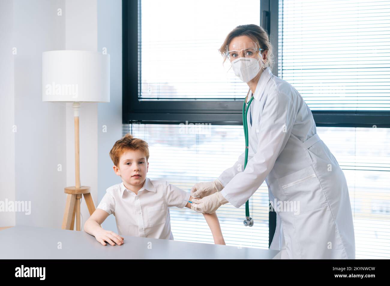 Portrait of female doctor applying plaster on shoulder of child boy ...
