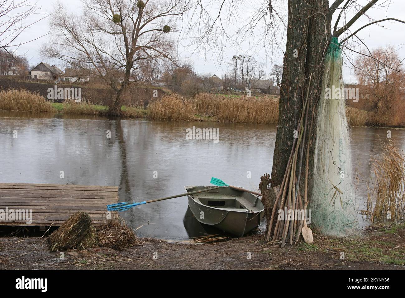 View of a frozen lake with smooth ice. Rowing boat and fishing nets ...