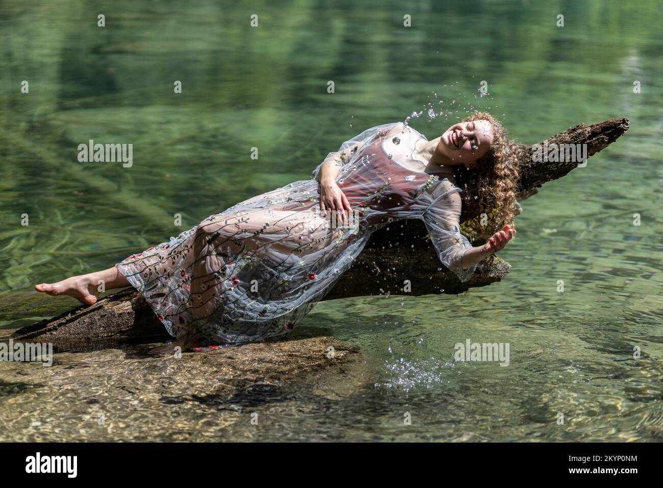 A young model plays with splashes on a mountain lake against the ...