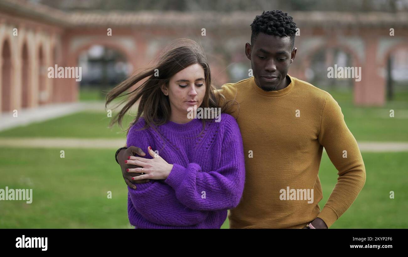 Young interracial couple walking together outside at park. Boyfriend ...
