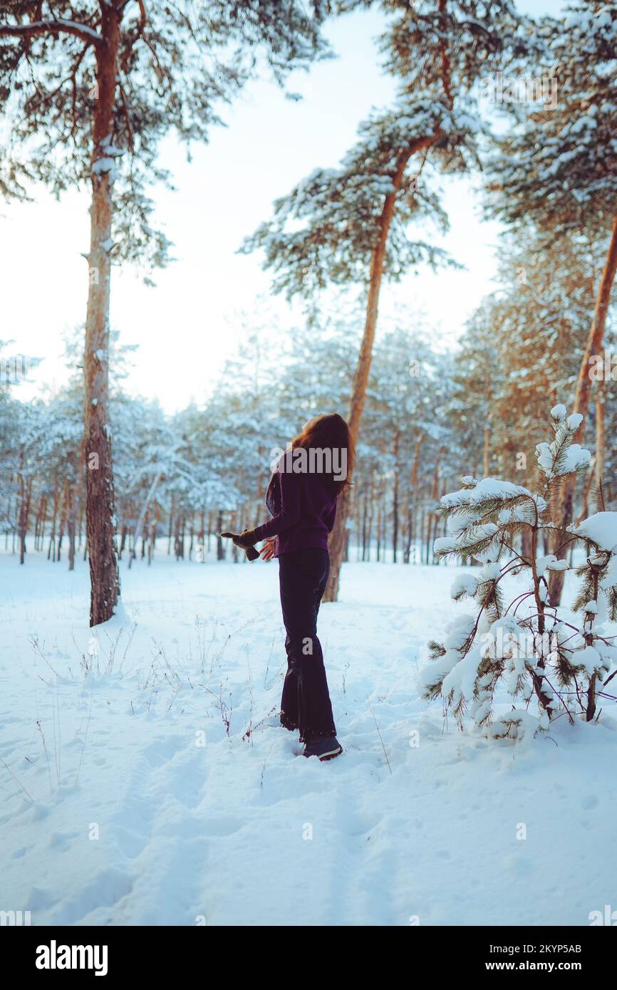 Young woman enjoying winter weather in the snow forest. Cold weather ...