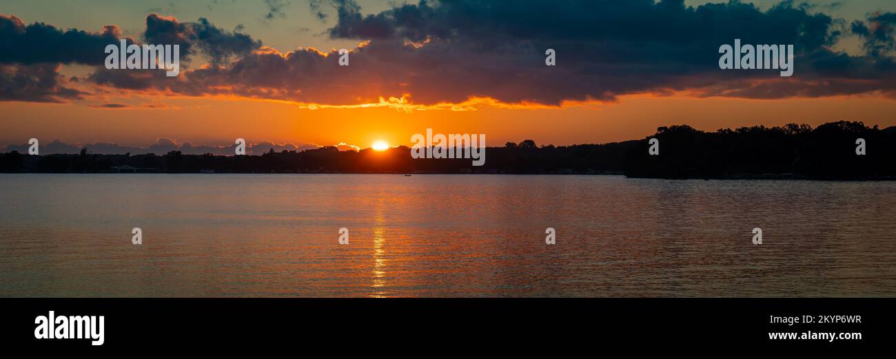 Serene sunset scene at a Minnesota lake with calm water and clouds and ...