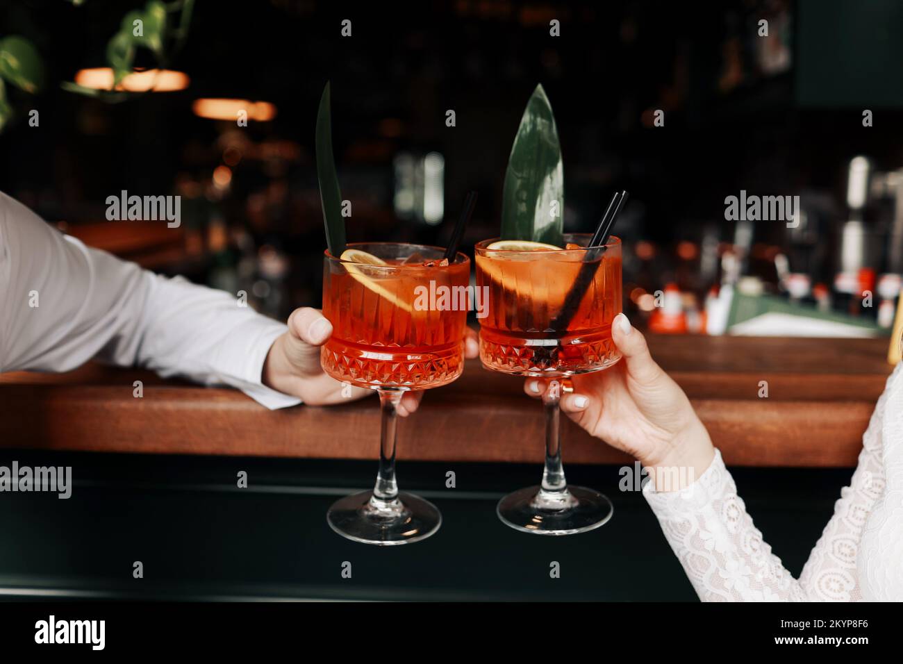 hands of woman and man are clinking, cheers with glasses of Spritz ...