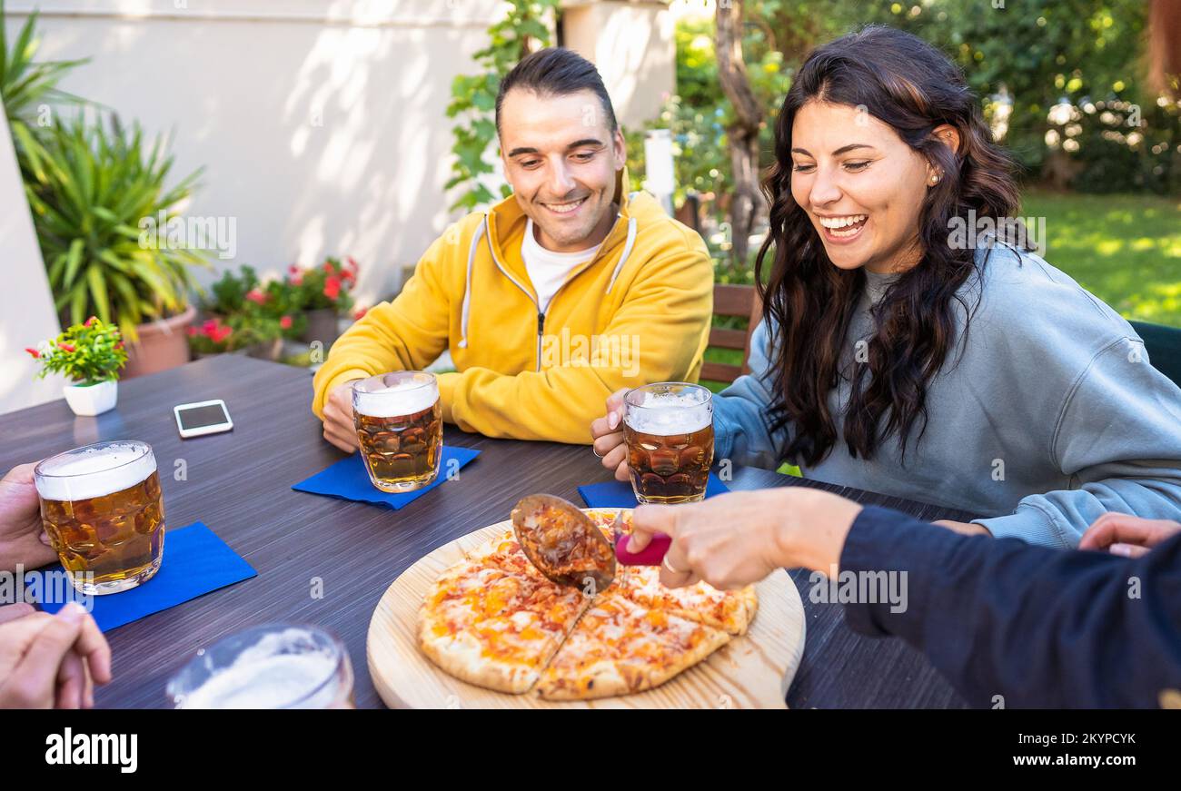Group of friends drinking pint of beer while waiting for pizza - Young ...