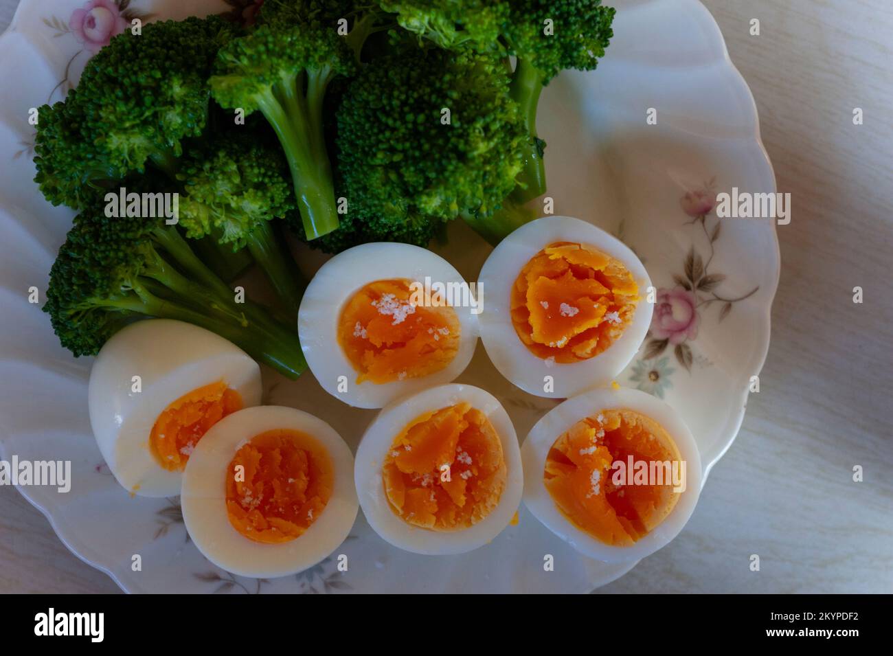 Boiled eggs, cut in half with bright orange yolks, and freshly blanched broccoli served at ...